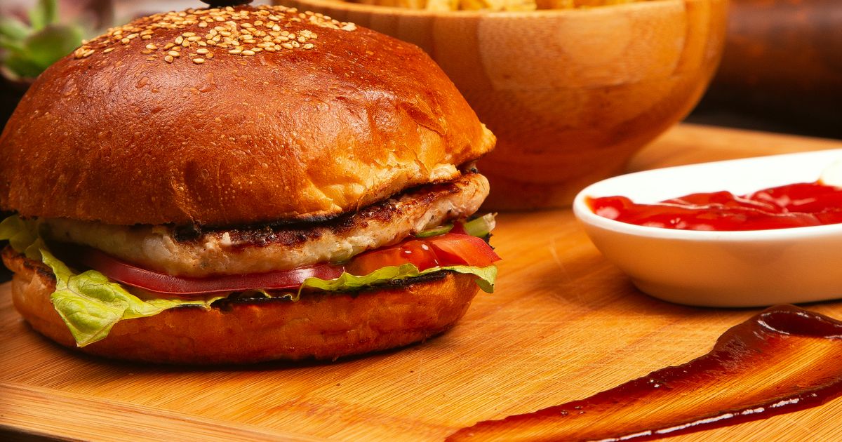 Burgeri cu carne de pui la grătar, felii de roșii și salată verde, o ...