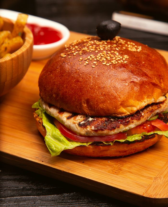 Burgeri cu carne de pui la grătar, felii de roșii și salată verde, o ...